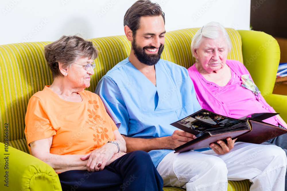 Altenpfleger schaut Fotos mit Senioren im Altenheim an Stock-Foto ...