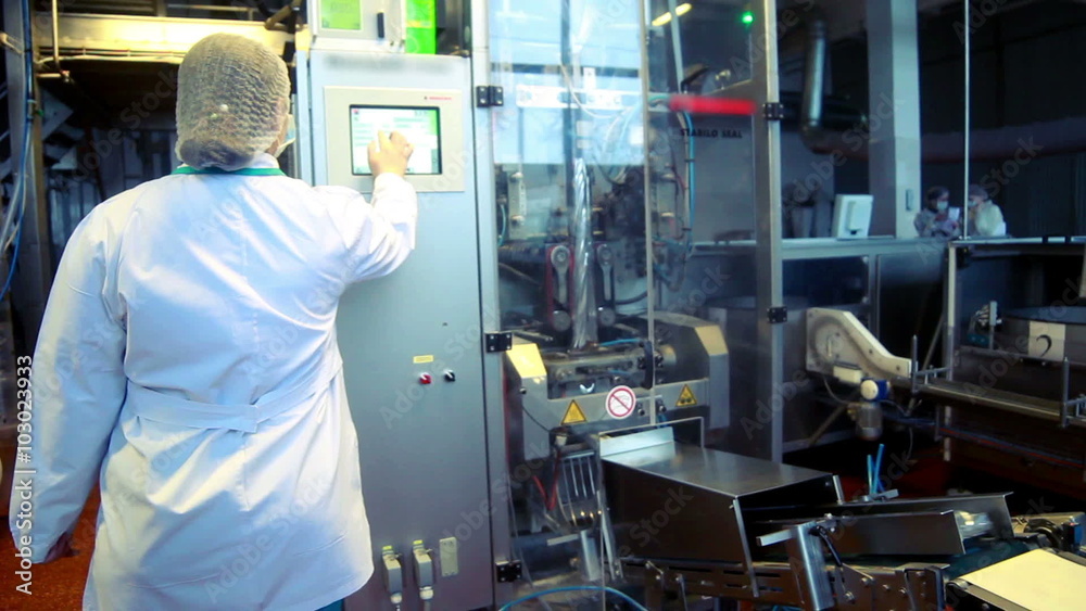 Worker operates industrial computer at factory/Factory worker operates ...