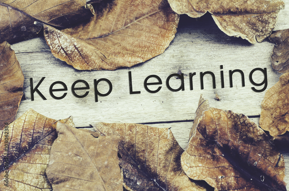 word KEEP LEARNING surrounded by dry leaves.old wooden background and ...