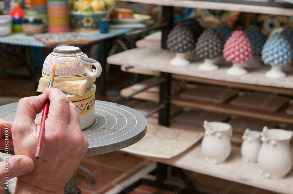 Poster A pottery decorator finishing a ceramic small cup with floral ...
