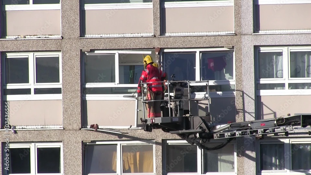 Two fire fighters on a hydraulic platform clearing debris from a ...