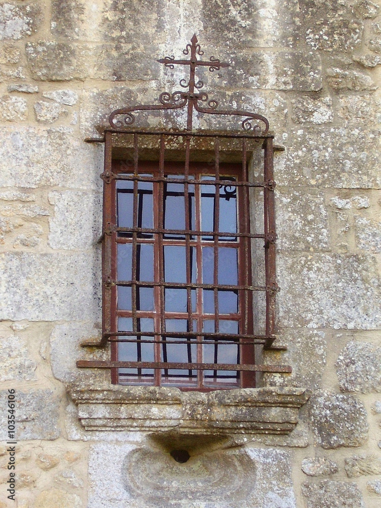 Medieval mullioned window with an ornate wrought iron security grill ...