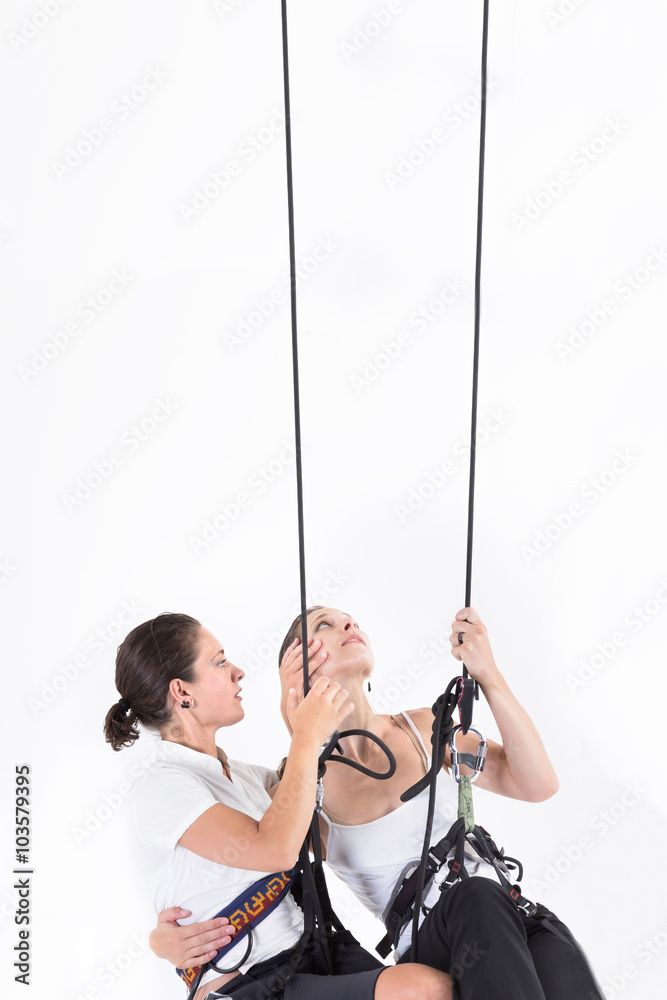 Two girls dressed executive with harnesses hanging from a climbing rope ...