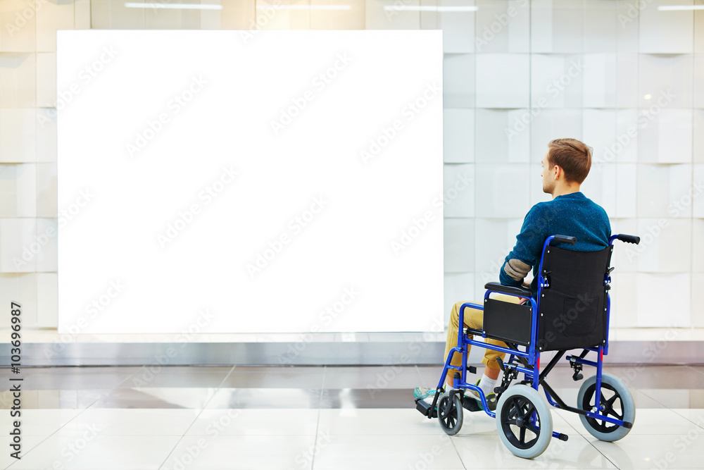 Disable guy in wheelchair looking at blank poster on the wall Stock ...