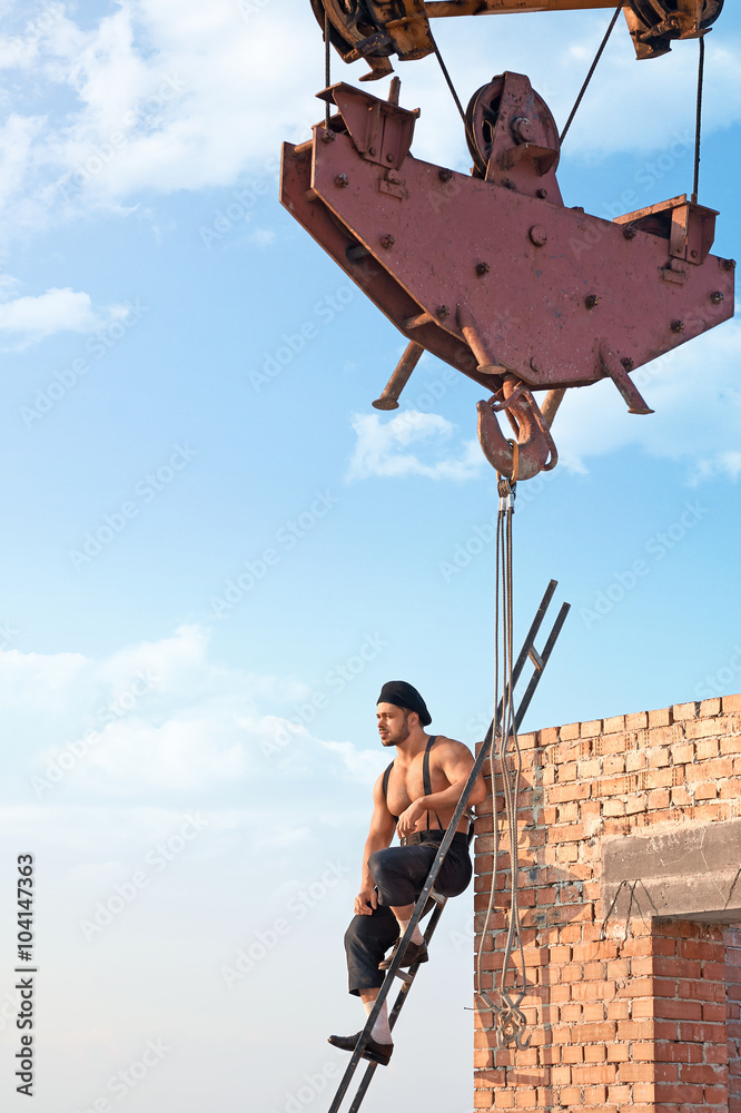 Resting a bit. Hunky shirtless builder sitting on a ladder at the ...