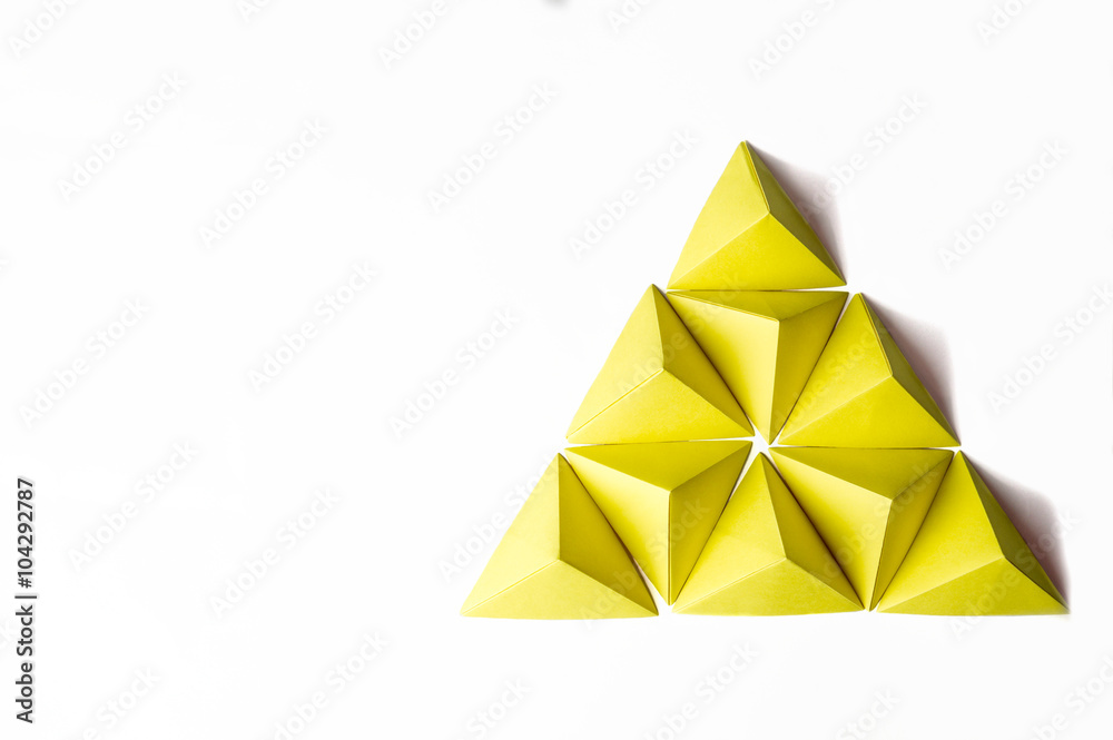 Yellow origami pyramid with tetrahedrons with copy space on the left ...