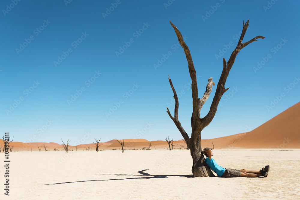 Namibia, Namib Desert, man resting at dead tree in Deadvlei Stock Photo ...