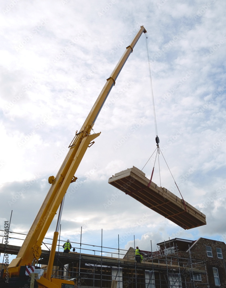 Industrial crane on a construction site lifting wooden panels Stock ...