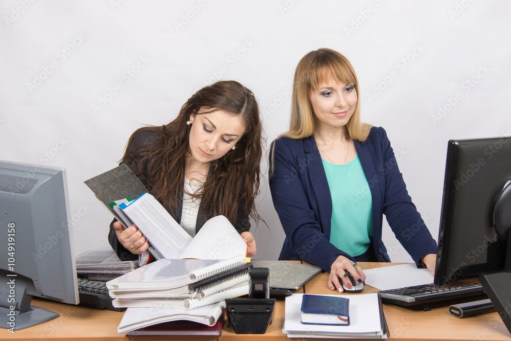 Female colleagues in the office, one works with paper documents, the ...