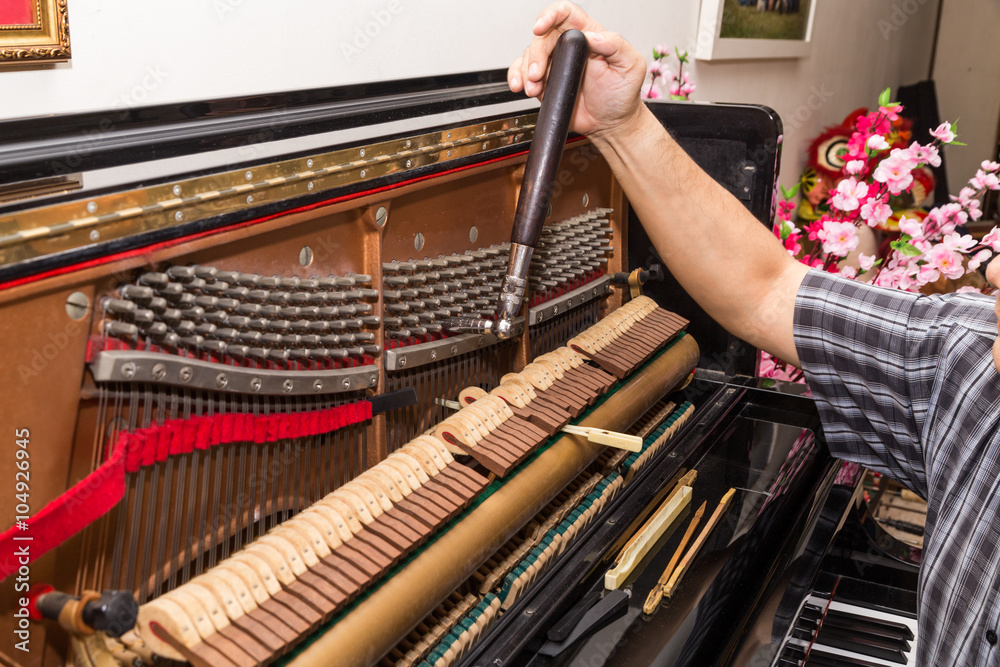 Closeup on hand tuning a upright piano using lever and tools ภาพถ่าย ...