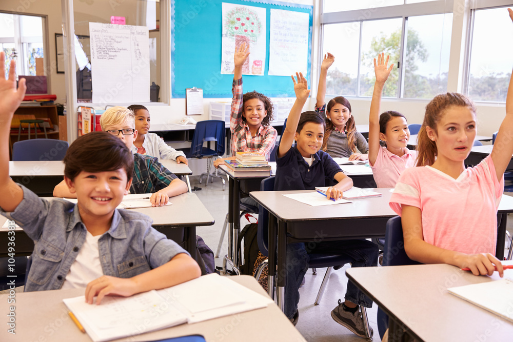 Elementary school kids in a classroom raising their hands Stock Photo ...