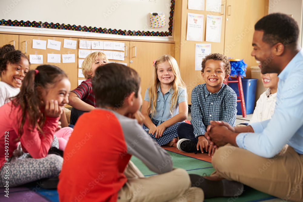 Elementary school kids and teacher sit cross legged on floor Stock ...