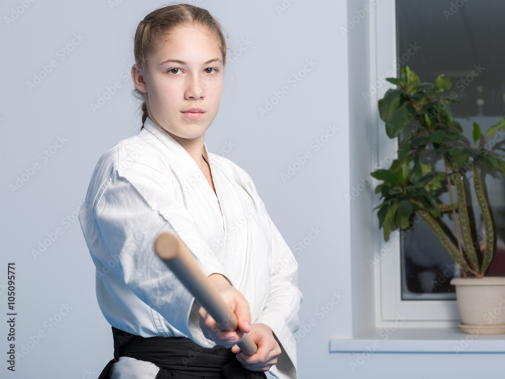 A girl in black hakama standing in fighting pose with wooden jo stick ...