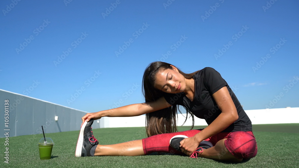 Seated one-legged toe touch woman stretching on outdoor fitness gym ...
