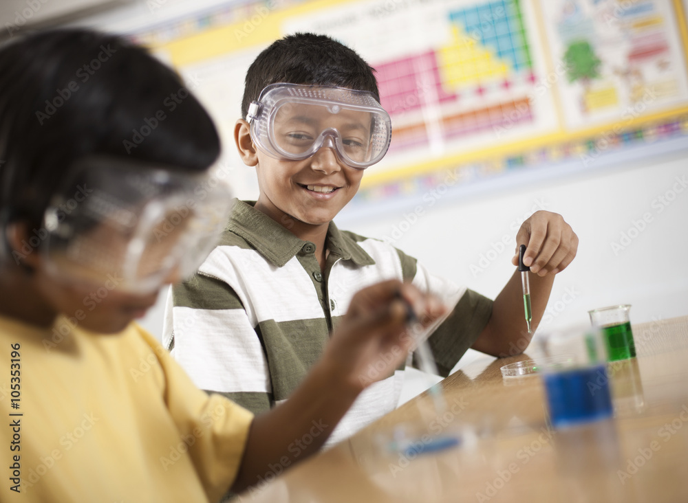Two young people, boy and girl in a science lesson, wearing eye ...