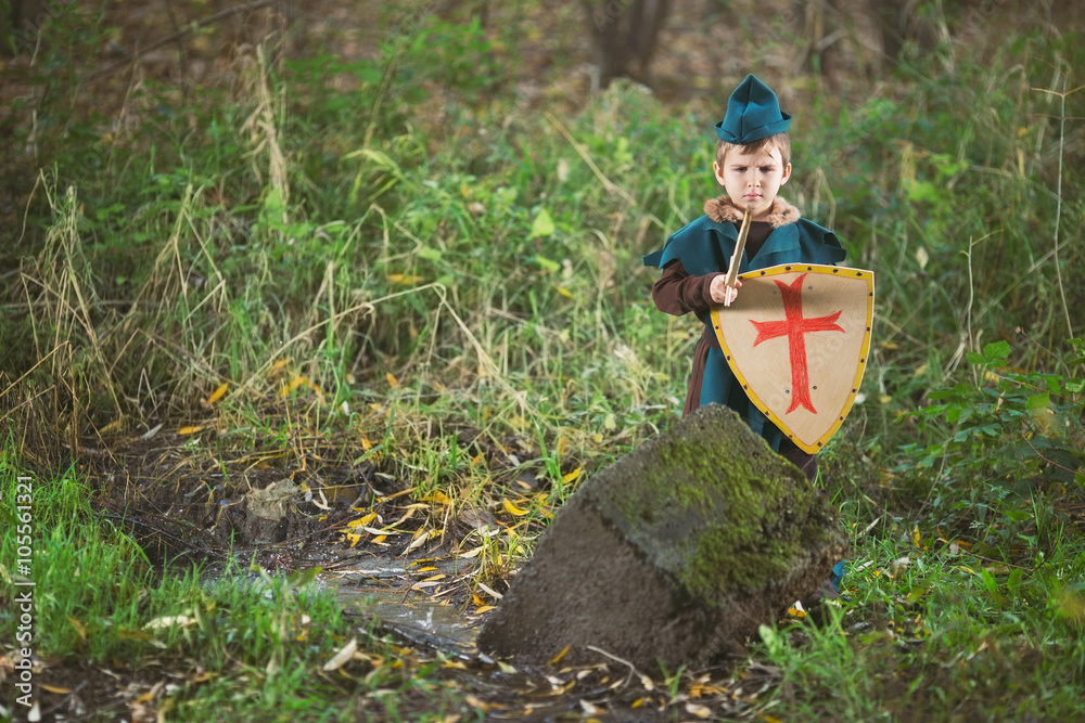 Cute little boy dressed as a knight playing with a sword and a shield ...