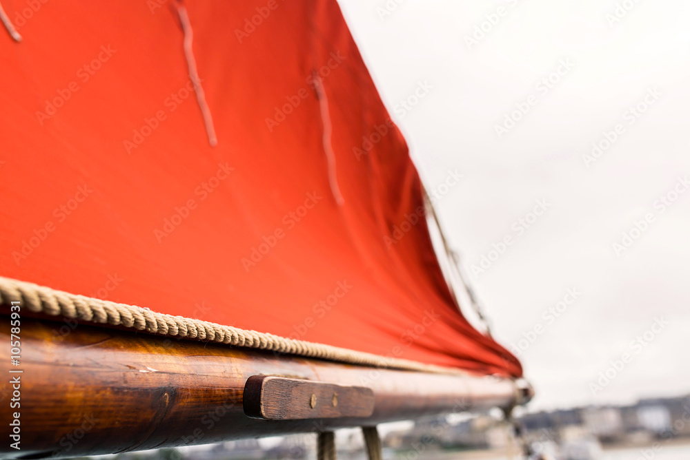 wooden boom with a rope and an ocher sail filled by the wind on an old ...