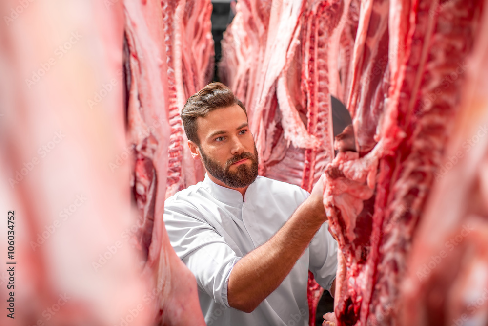 Handsome butcher cutting pork carcasse at the meat manufacturing Stock ...