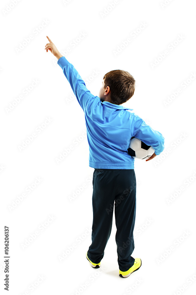 Back view of little boy holding football, points at wall. Rear view ...