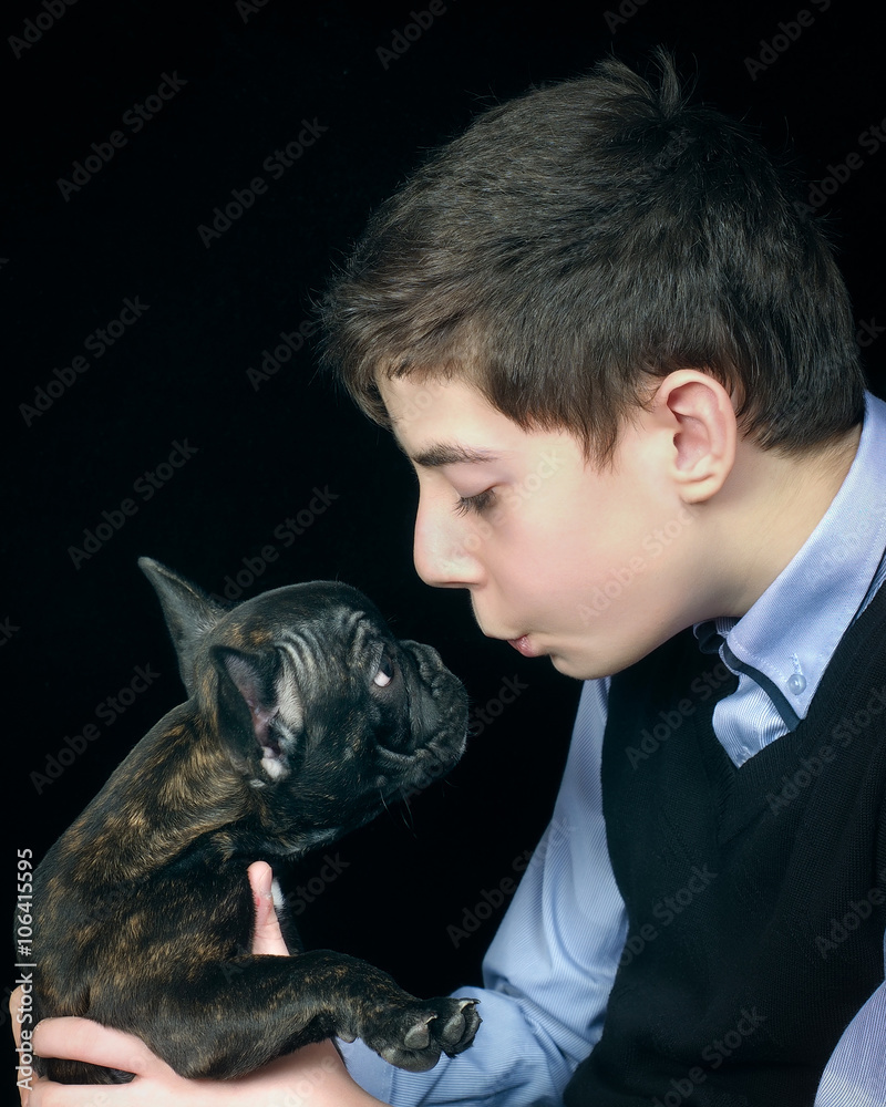 Portrait of a teenage boy with a dog. The boy looks at the French ...