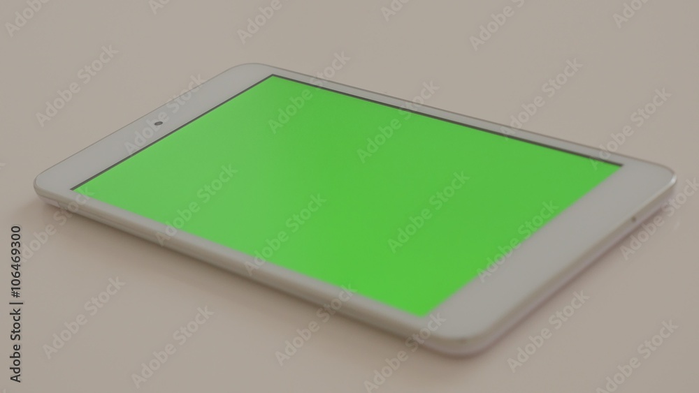 Silver tablet PC with green screen on display tilting on white surface ...