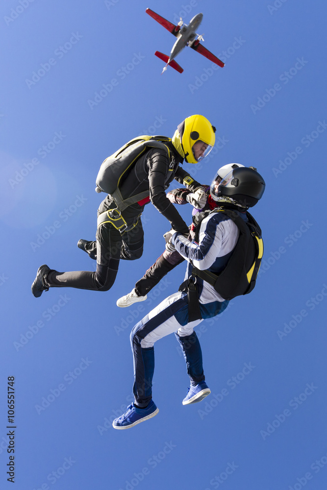 Two girls and a guy skydivers jump out of an airplane. Stock Photo ...