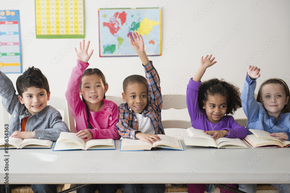Students raising hands in classroom Stock Photo | Adobe Stock