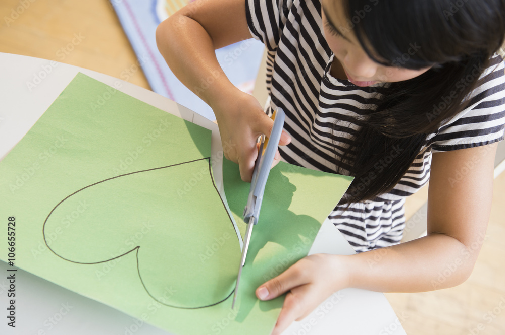 Filipino girl cutting heart shape out of paper Stock Photo | Adobe Stock