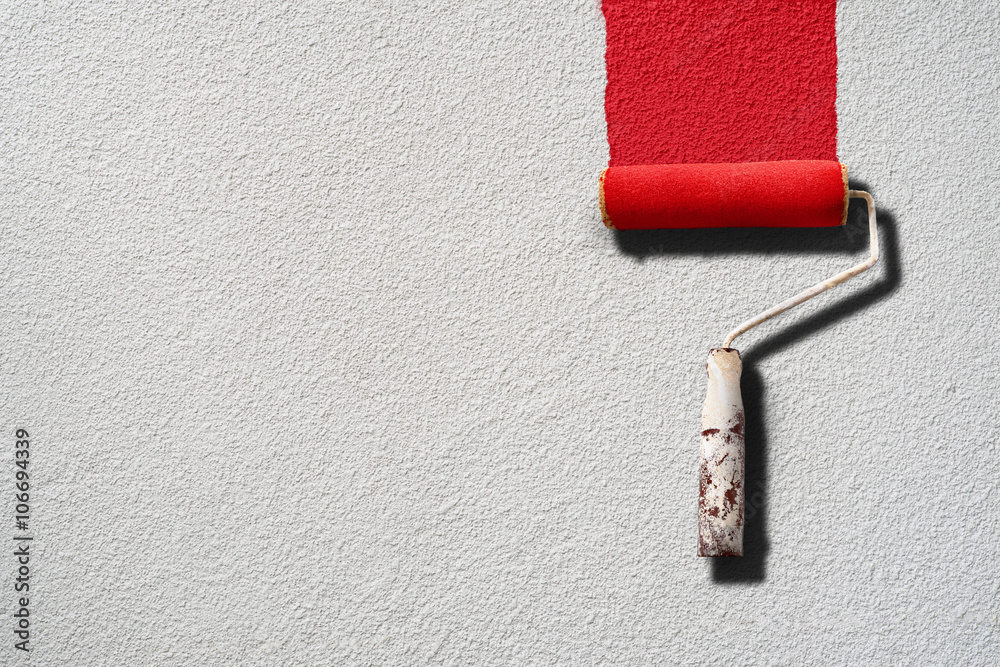 Paint roller painting with red paint on white wall with rough texture ...