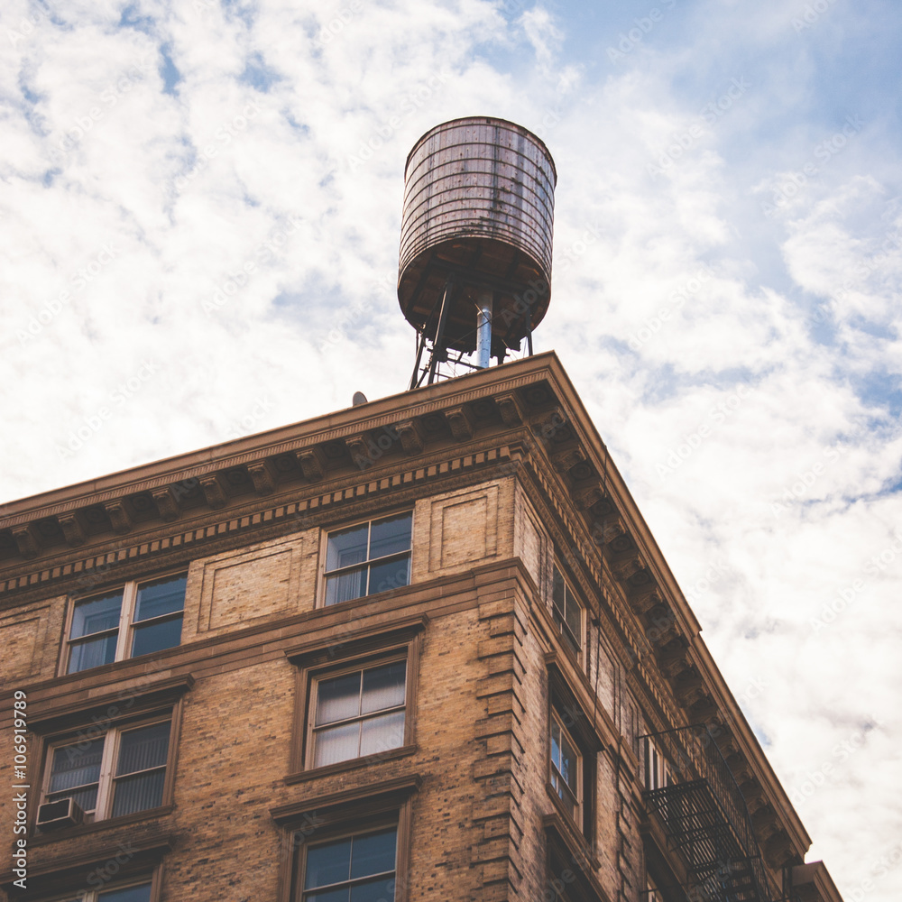Water tank, sitting on top of a apartment building, on the backdrop of ...