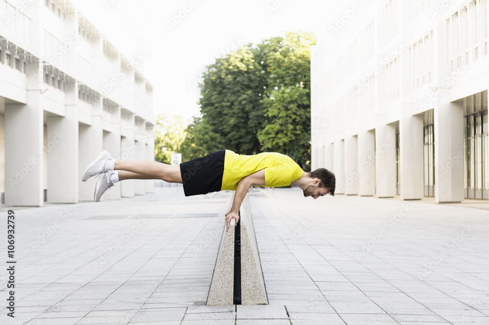 Young man balancing horizontally on divider Stock Photo | Adobe Stock