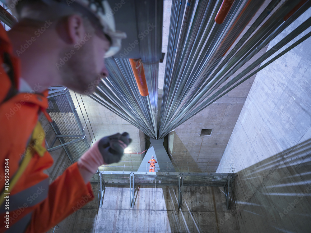 Civil engineers inspecting cable anchorage in suspension bridge, low ...