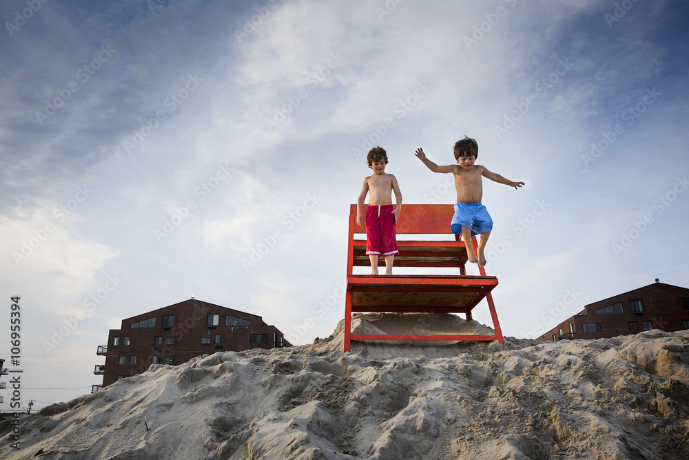 Two boys jumping off red notice board, Long Beach, New York State, USA ...