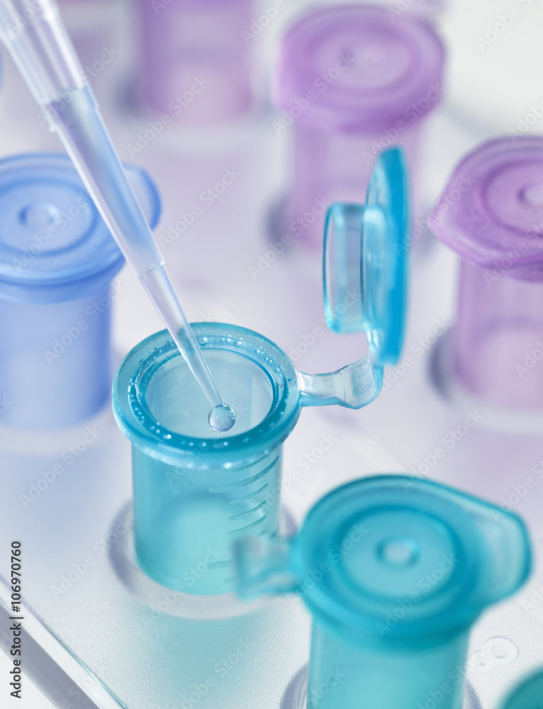 Pipette dropping a solution into a vial, used for storing liquid during ...