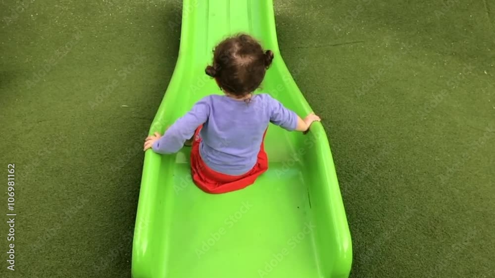 Slow motion of a little girl (age 1-2) slide down on a slide in the ...