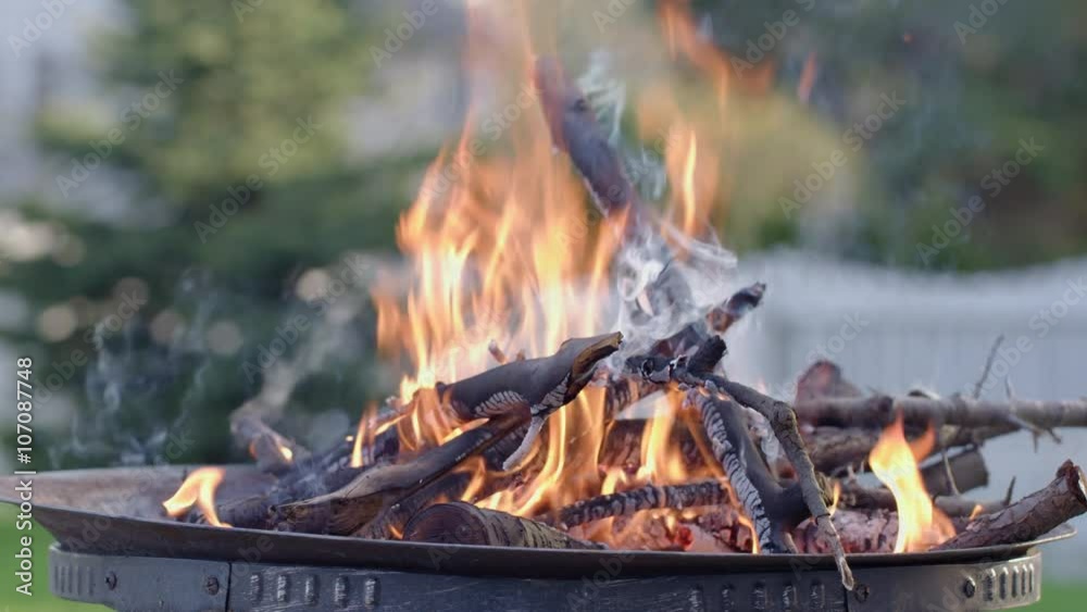 Flames rising up from burning pile of sticks in a fire pit. Wide view ...
