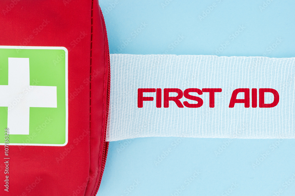 Red first aid kit with unrolled gauze with First Aid text, on light ...