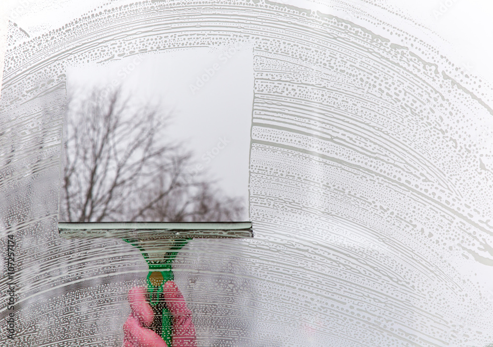 Hand in pink protective glove washing and cleaning window with ...