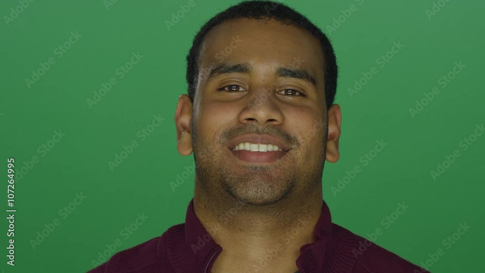 Young African American man smiling and nodding his head, on a green ...
