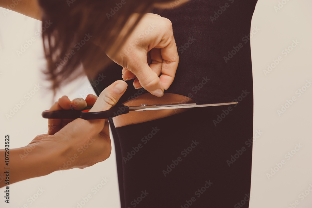 female hands scissor, cutting tights on beautiful woman legs in black ...
