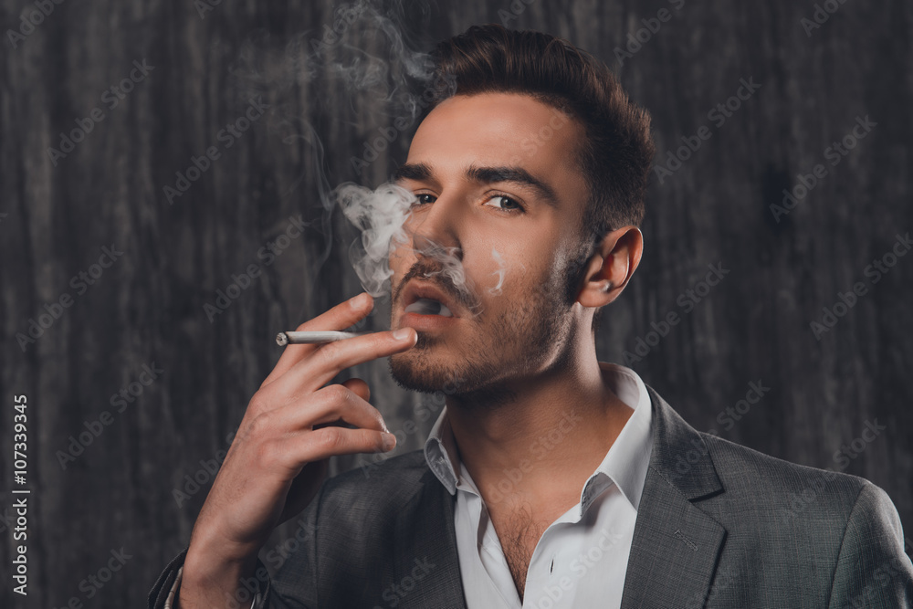 Handsome brutal man in gray suit smoking a cigarette Stock Photo ...