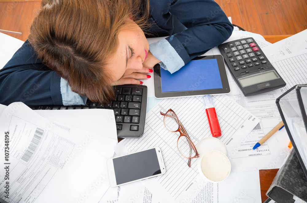 Young woman sitting and lying asleep over office desk with papers ...