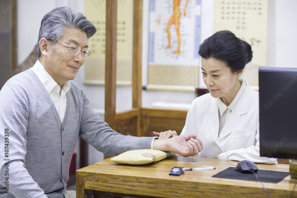 Female Chinese doctor taking the pulse of patient Stock Photo | Adobe Stock