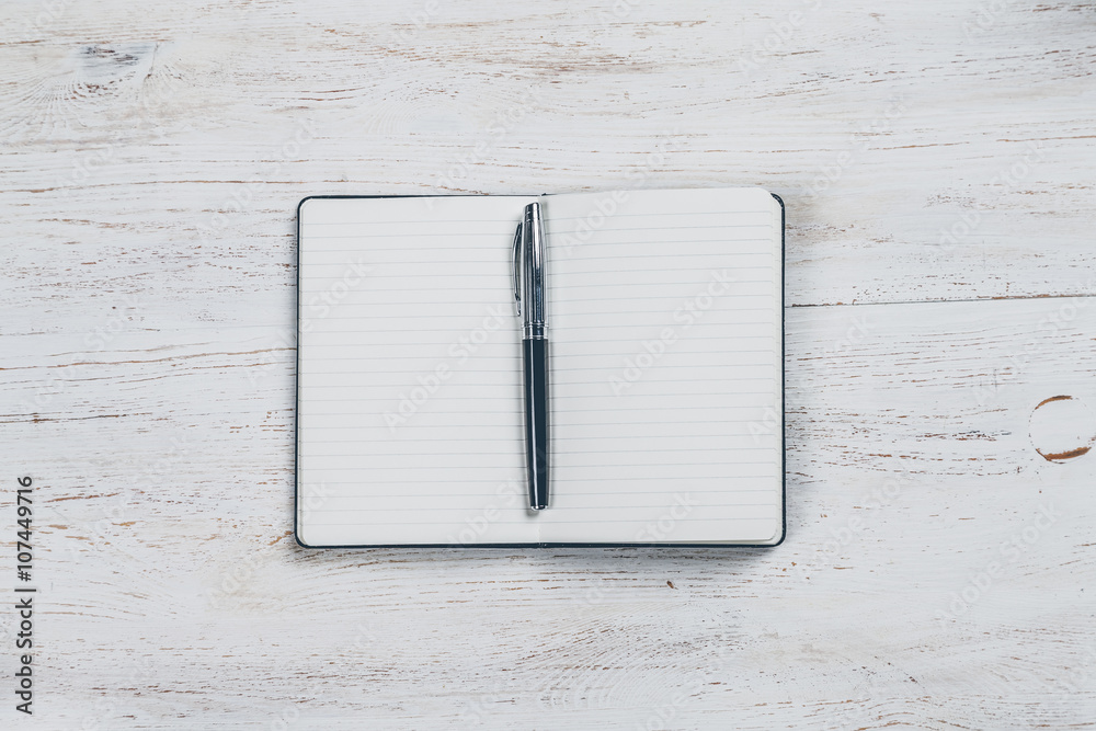 A lined notebook for notes is placed on a table in white lacquered wood ...