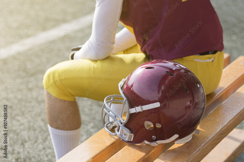American football player sitting on bench and helmet next to him Stock ...