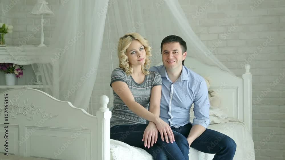 A happily married couple. Husband and wife sitting on the bed. The ...