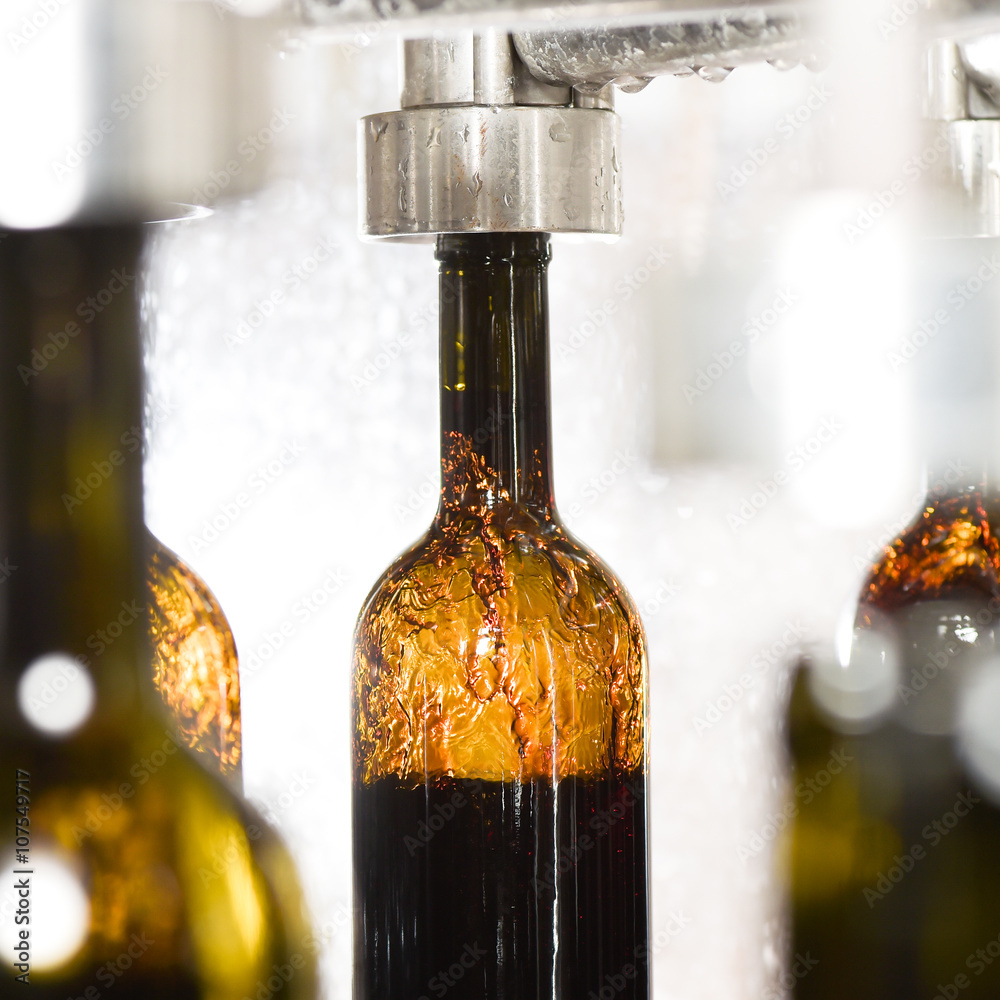Foto de Wine bottle filling along conveyor belt in bottling factory do ...