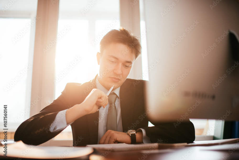 Professional business man at office working at his desk, holding a pen ...