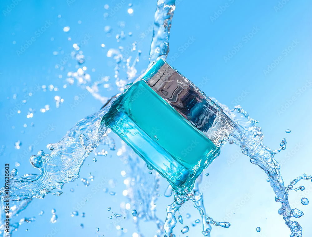 The blue jar of moisturizing cream with big water splash around the jar ...