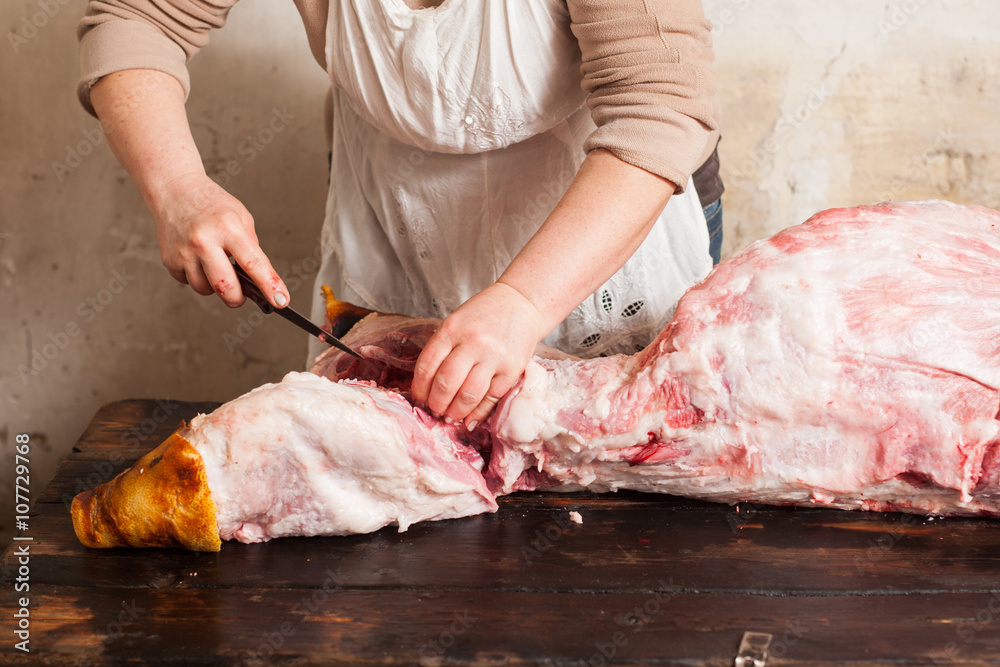 Butcher carving raw pork in local market. Butcher curving a carcass of ...